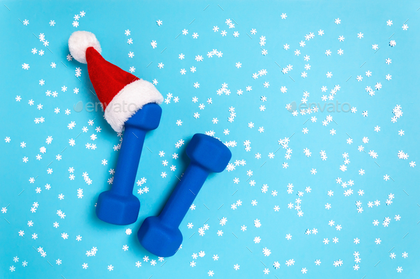 Christmas sport flat lay with dumbbells in red Santa's hat on blue ...