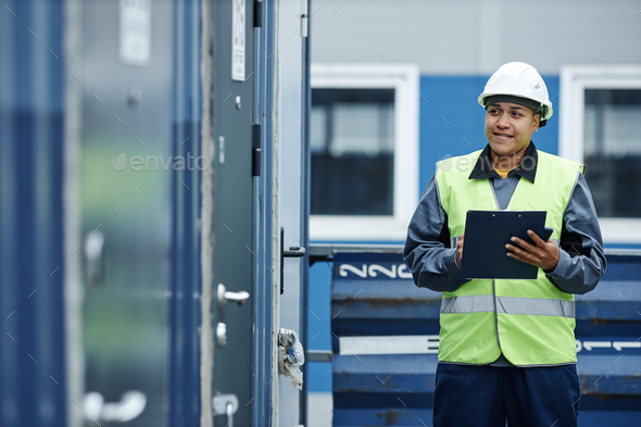 Smiling female worker at shipping docks Stock Photo by seventyfourimages