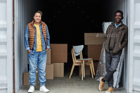 Smiling young people standing inside shipping container Stock Photo by ...