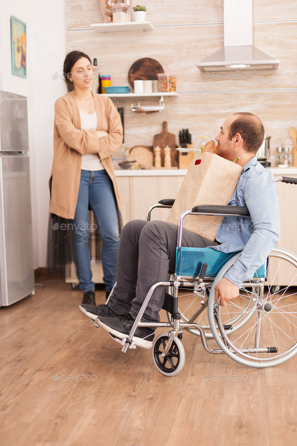 Invalid man in wheelchair with groceries bag Stock Photo by DC_Studio