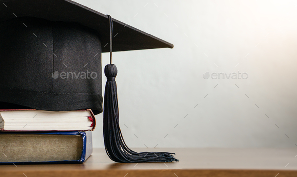 Mortar board with degree paper and books on wood table. graduation ...