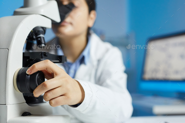 Scientist using adjustment knob of microscope Stock Photo by Media_photos