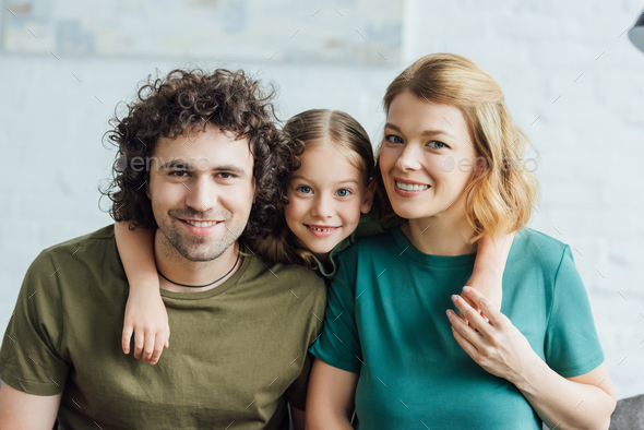 happy family with one child embracing and smiling at camera Stock Photo ...