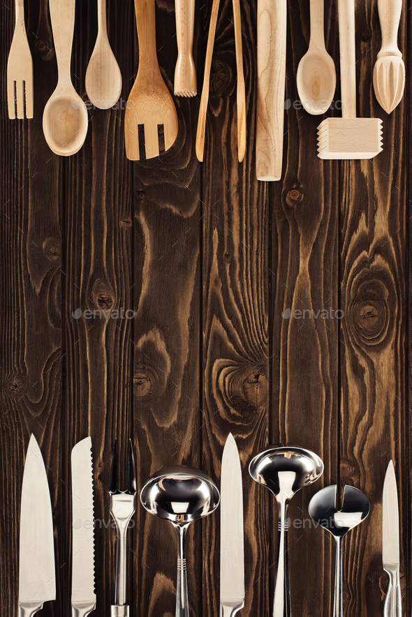 top view of metallic and wooden kitchen utensils placed in two rows on ...