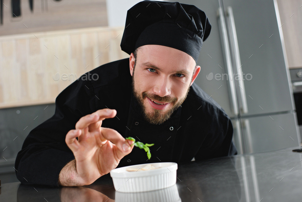 handsome chef adding herb to dish at restaurant kitchen Stock Photo by ...