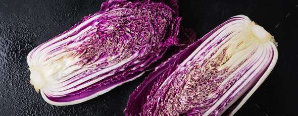 Fresh raw purple Chinese cabbage cut in half on a black concrete old ...