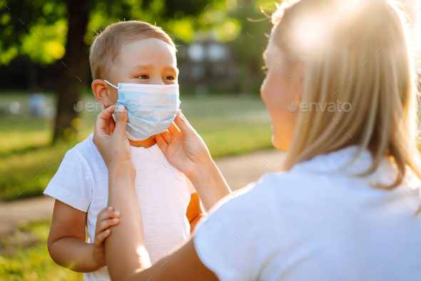 Mother puts on her baby sterile medical mask at sunset during pandemic ...