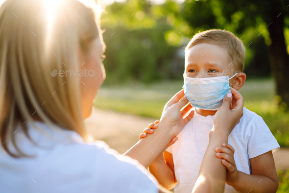 Mother puts on her baby sterile medical mask at sunset during pandemic ...