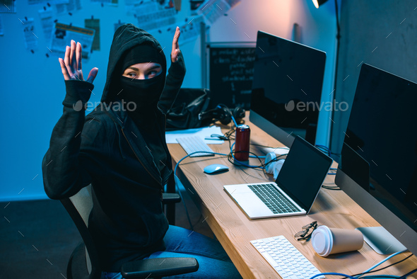 busted hacker in mask with raised hands in front of workplace Stock ...