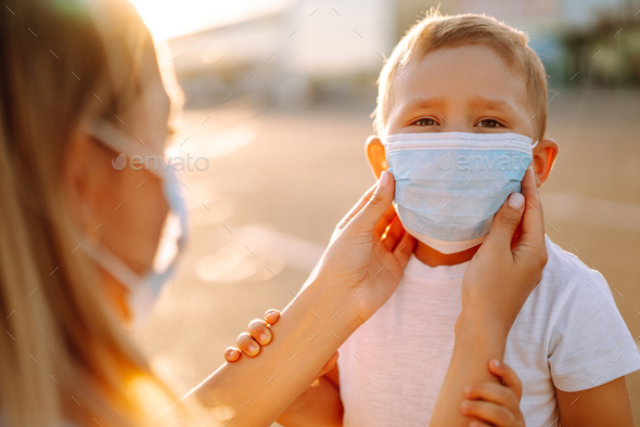 Mother puts on her baby sterile medical mask at sunset during pandemic ...
