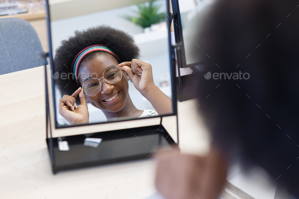 Close up mirror with face of young woman African American afro hair ...