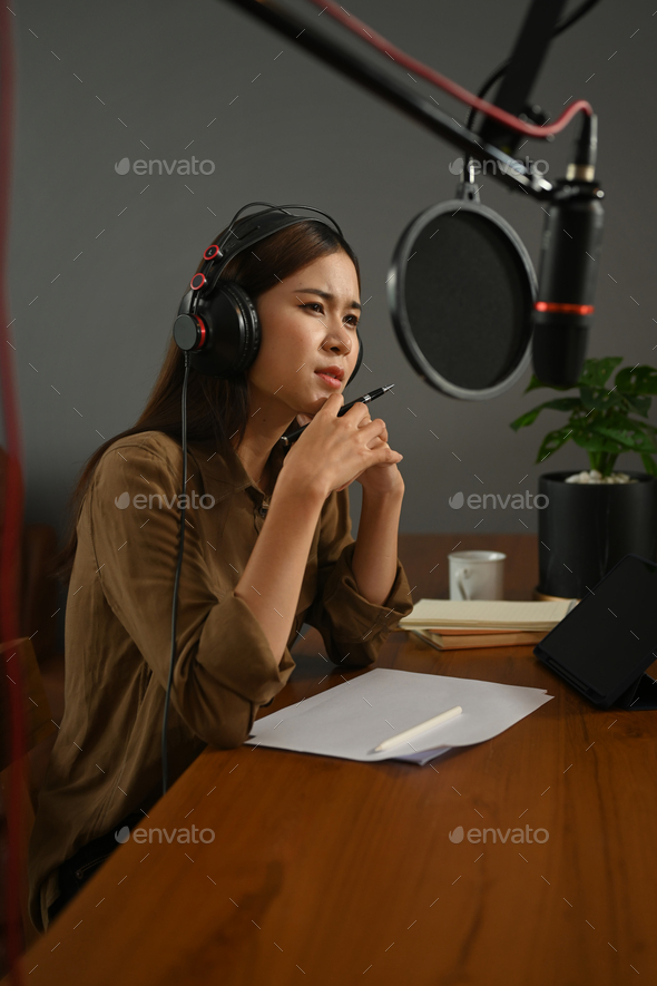 Female radio hosts wearing headphone sitting near microphones and ...