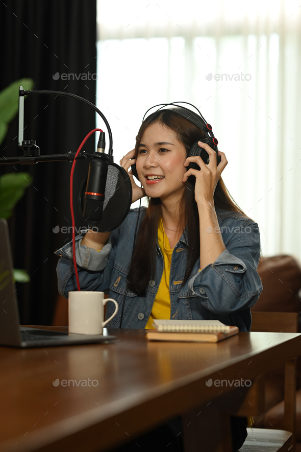 Young female content creator using microphone and headphones to ...