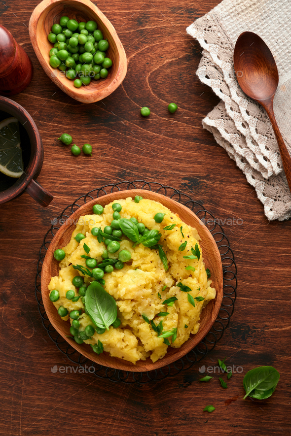 Mashed potato with butter, green peas, onions, basil on a rustic wooden ...