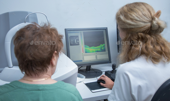 an elderly woman on a CT scanner does a retinal tomography in the ...