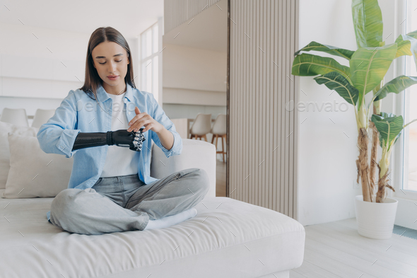 Female amputee is adjusting electronic artificial arm at home ...