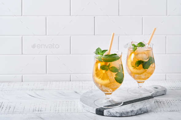 Traditional iced tea with lemon and ice in tall glasses on marble table ...