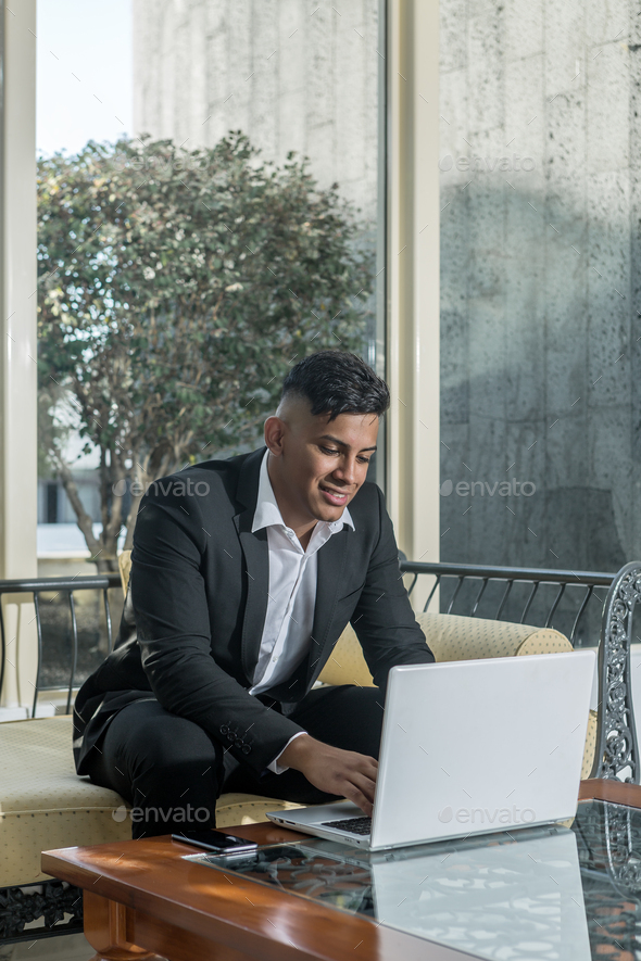 Smiling ethnic entrepreneur using laptop Stock Photo by Juan_Algar