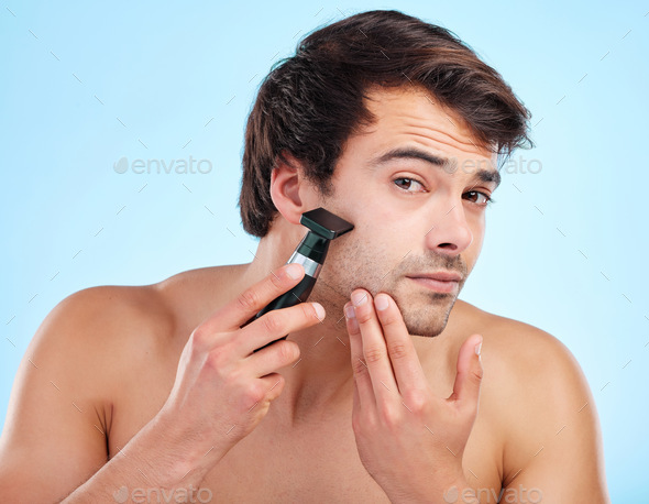 Just one quick shave. Shot of a young man shaving his face against a ...