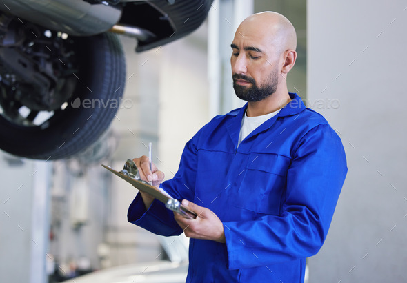 Cropped shot of a handsome young male mechanic working on the engine of ...