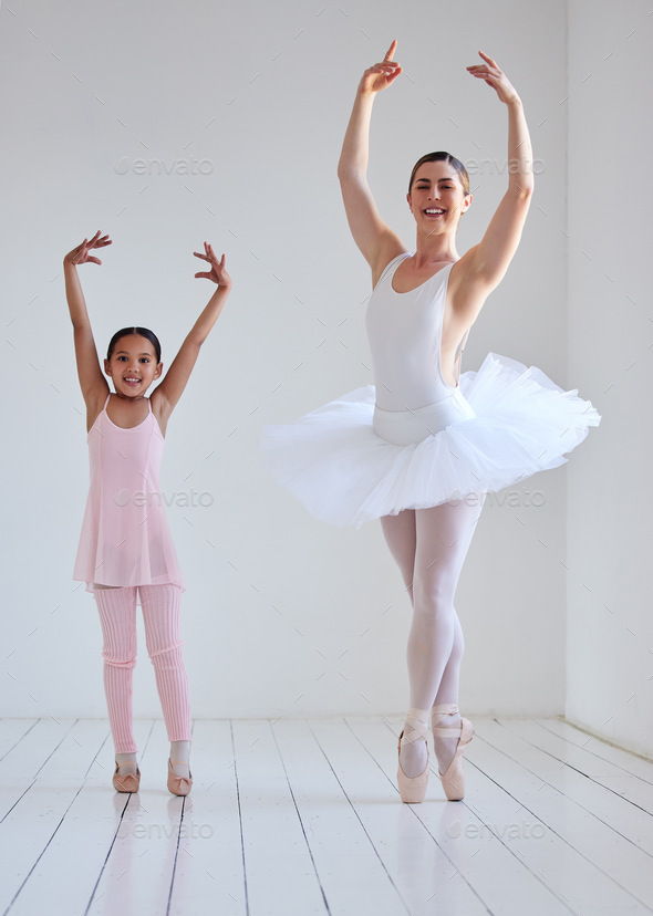 Portrait of a little girl practicing ballet with her teacher in a dance ...