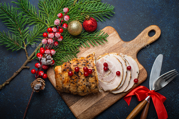 Christmas baked ham sliced with red berries and festive decorations ...
