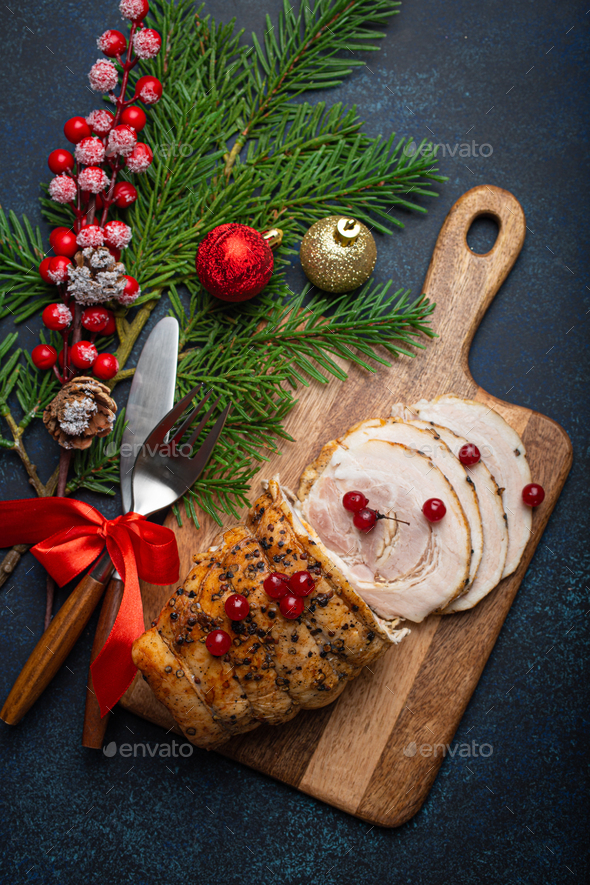 Christmas baked ham sliced with red berries and festive decorations ...