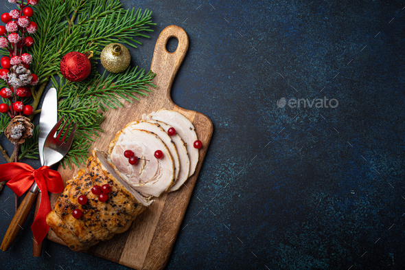 Christmas baked ham sliced with red berries and festive decorations ...