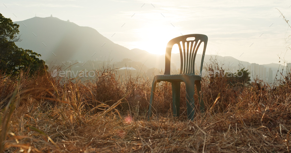 Sunset sunlight flare over the chair in tall grass Stock Photo by ...