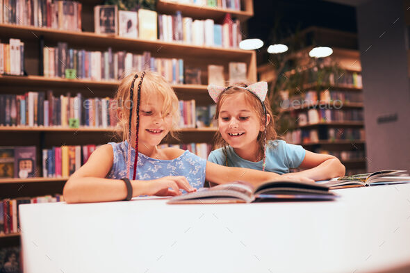 Two elementary schoolgirls doing homework in school library. Students ...