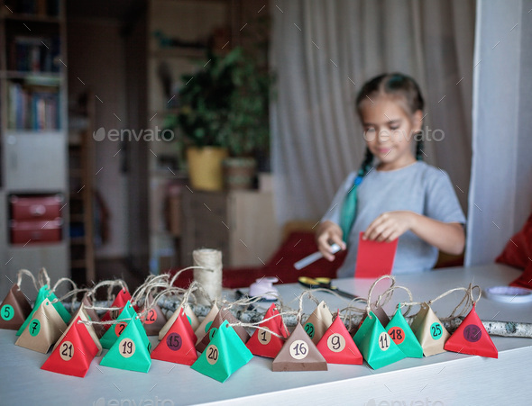 Girl making handmade advent calendar with color paper triangles ...