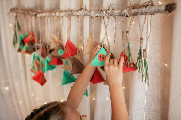 Girl opening handmade advent calendar with color paper triangles ...