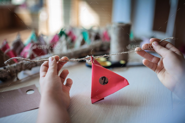 Girl making handmade advent calendar with color paper triangles ...