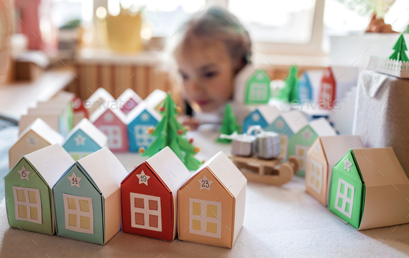 Origami advent calendar. Girl looking upon tiny paper houses, Christmas ...