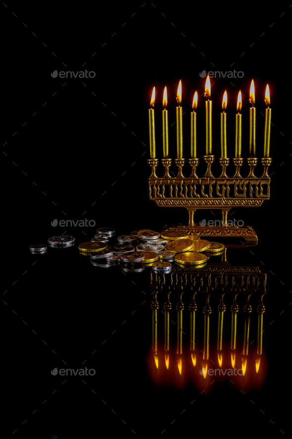 Menorah with golden candles, chocolate coins and reflection on surface ...