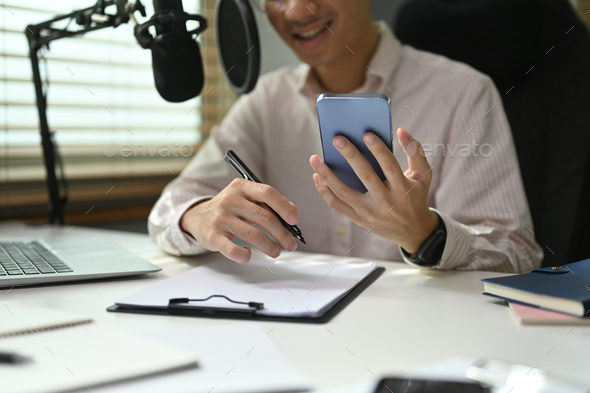 Male podcaster wearing sitting front of condenser microphone and using ...
