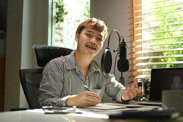 Confident male podcaster sitting front of condenser microphone and at ...