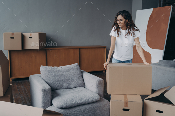 Smiling european woman is packing things. Young lady is unpacking ...