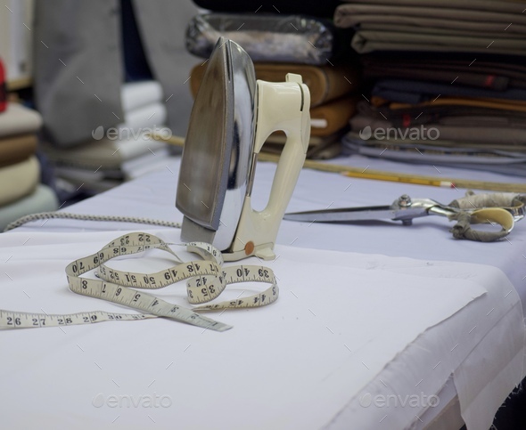 A local tailor’s work station with steam iron, shears, scissors, and ...