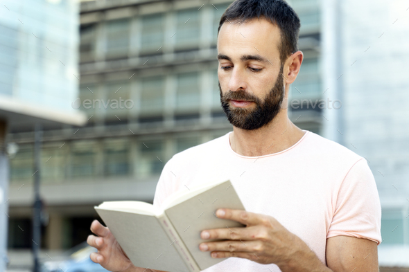 Man reading book outdoors. Pensive student studying, learning something ...