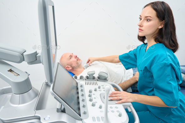 Nurse is attaching electrocardiogram equipment to a wrist of patient ...
