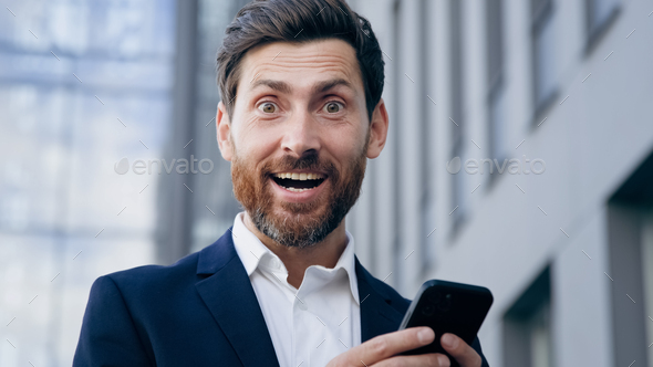 Close-up excited surprised man reading email notification on mobile ...