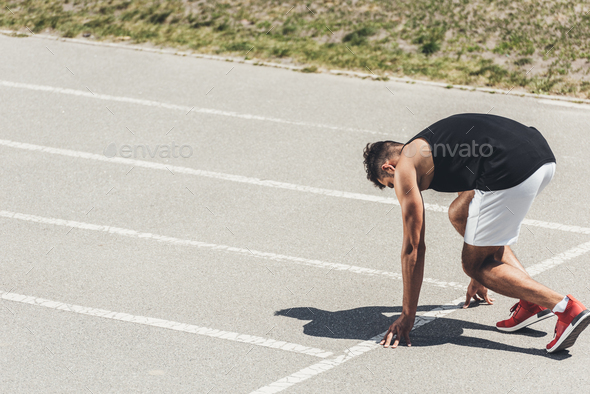 young male sprinter in starting position on running track Stock Photo ...