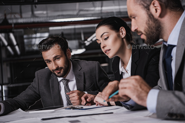 engineer colleagues in formal wear working with blueprints together ...