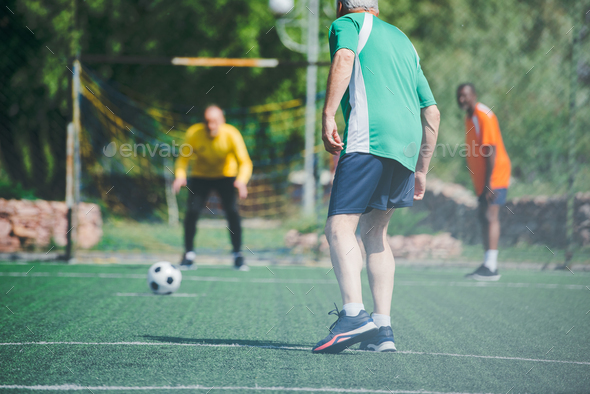 multiracial old men playing football together on green field Stock ...