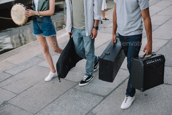 Cropped view of street musicians walking and carrying musical ...