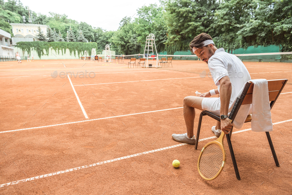 tennis player sitting on chair with tennis ball, retro wooden racket ...