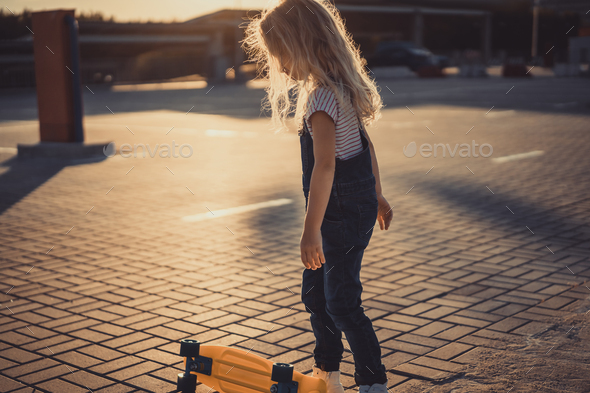 side view of little child standing near skateboard at parking lot Stock ...