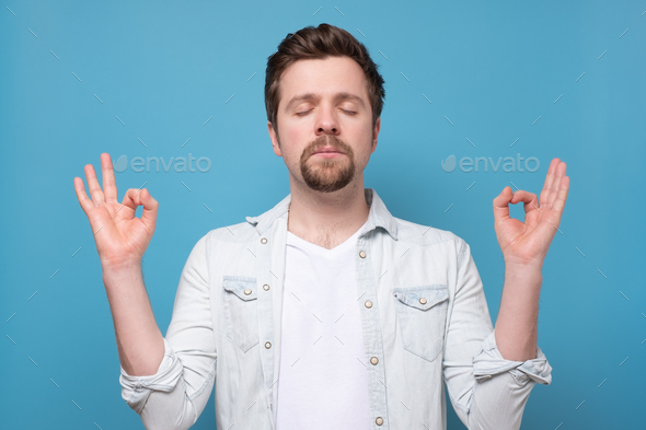 Handsome guy meditating with raised hands and zen gesture, being ...