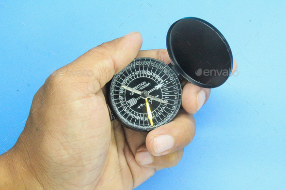 Hand holding a compass showing the direction of Kaaba or Qibla in ...